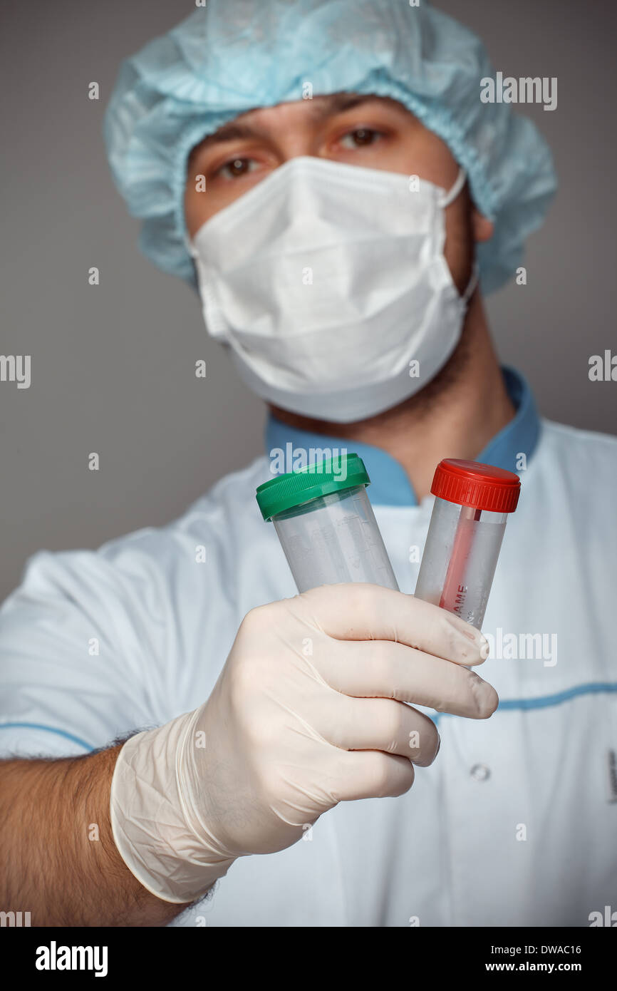 young doctor with container for analysis. with emotions under the mask ...