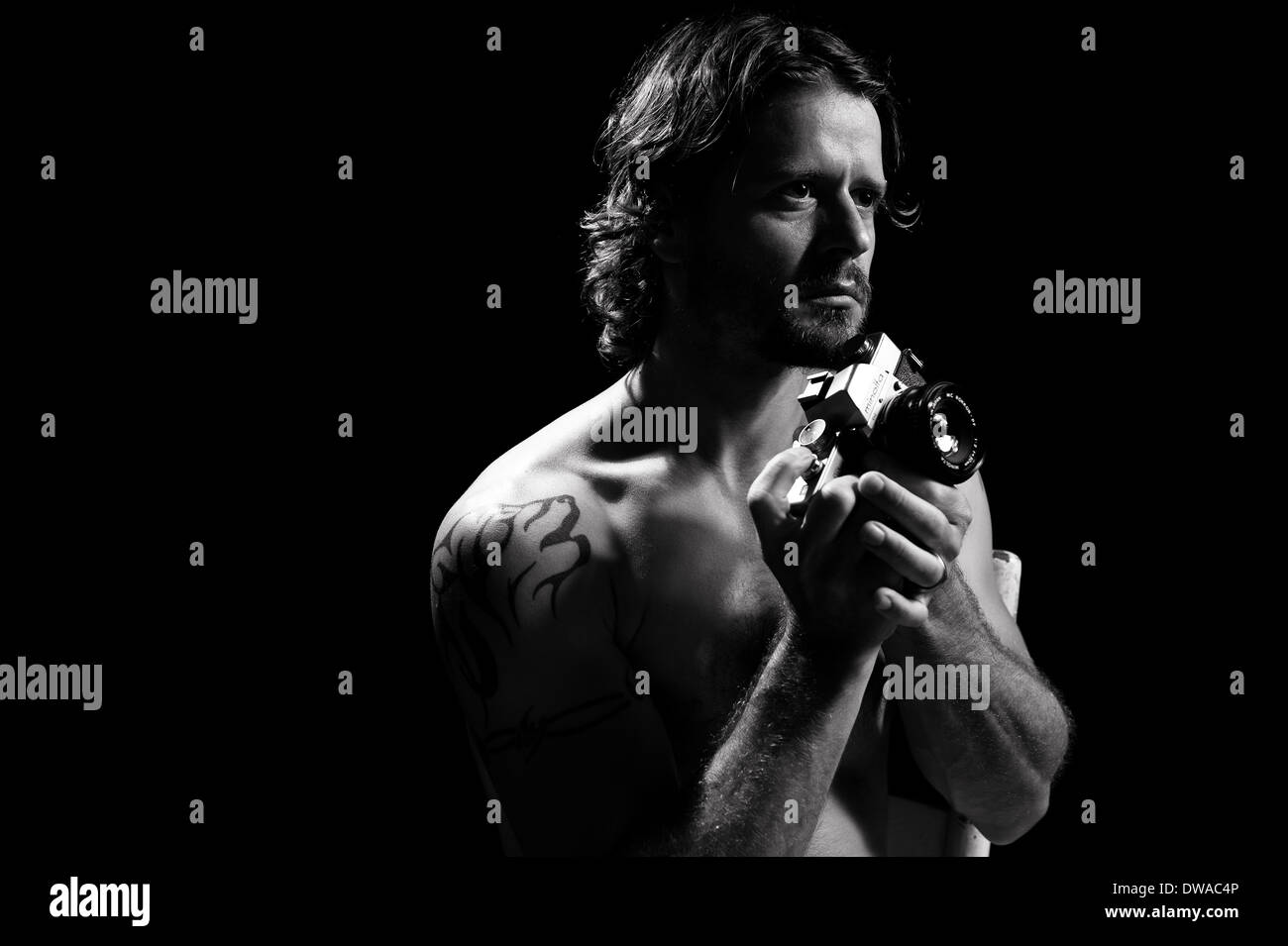 Artistic, low-key studio portrait of young man holding a classic analog ...