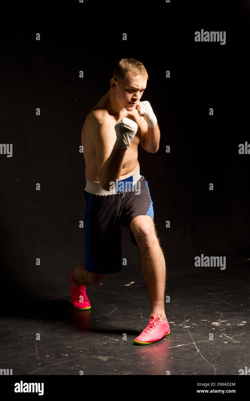 Barechested muscular young boxer training in the ring with bandaged ...