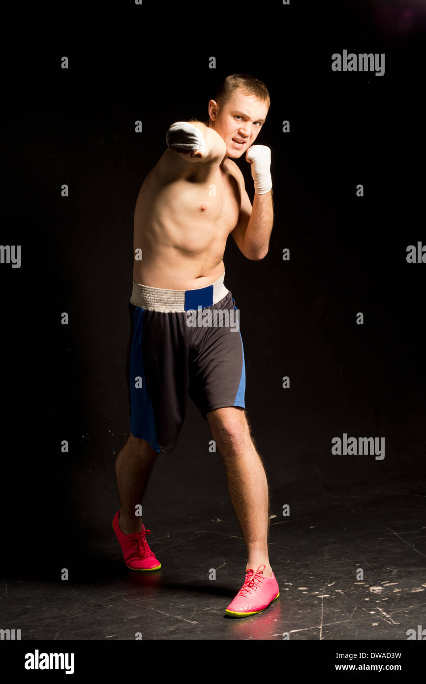 Belligerent young boxer throwing a punch at the camera as he works out ...