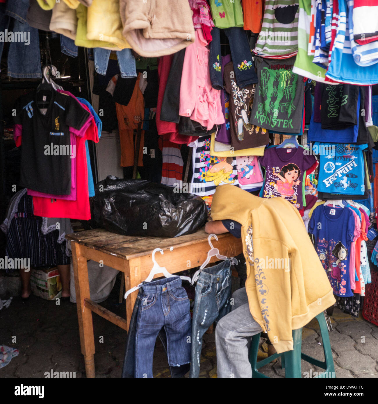 Market trader sleeps at his stall selling clothes in Antigua market ...