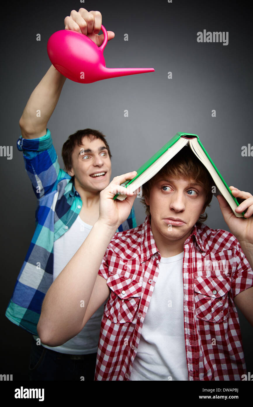 Freaky guy pouring water over his friend hiding under a book, fool’s ...
