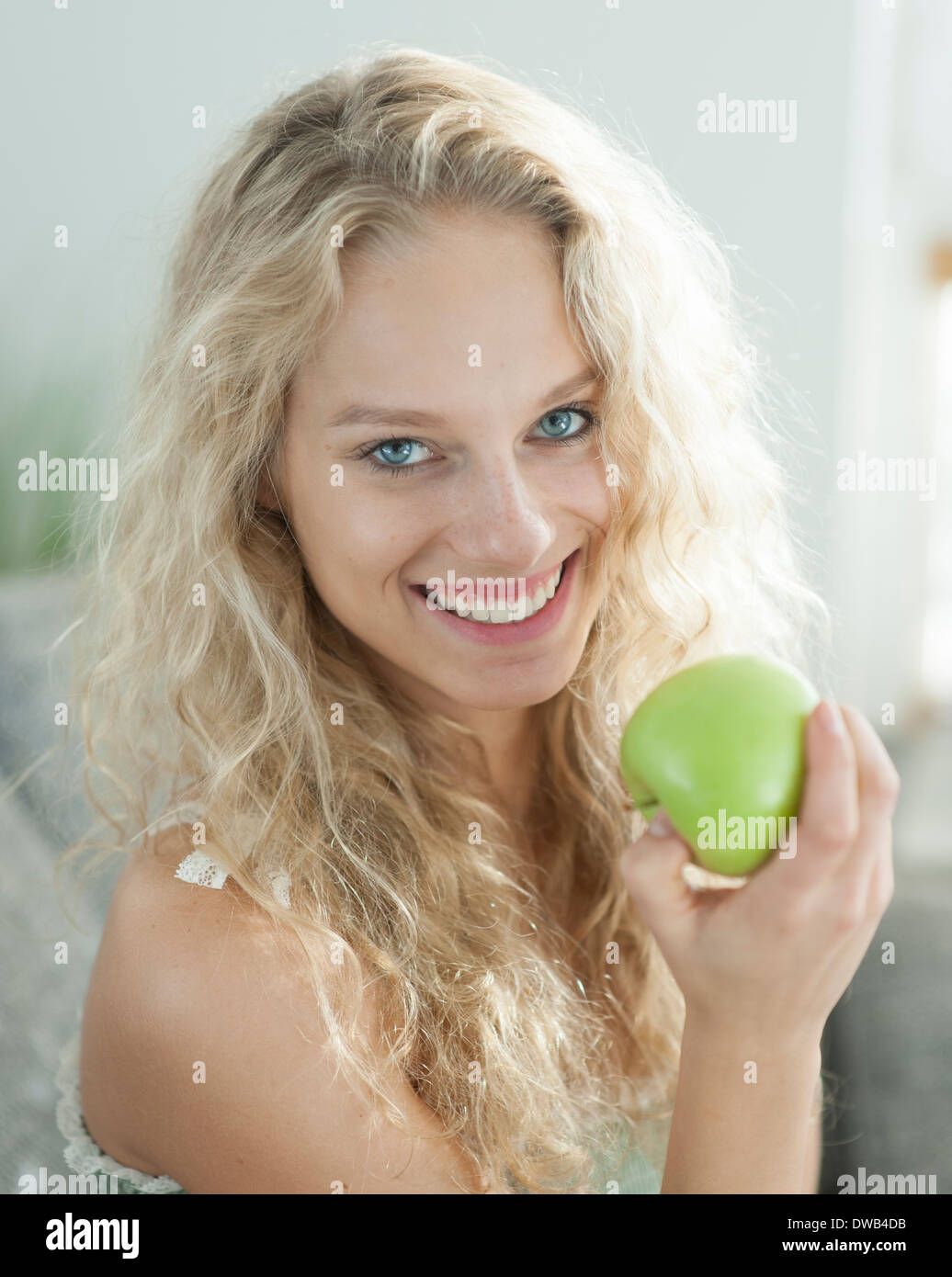 Portrait of happy young woman holding apple in house Stock Photo - Alamy