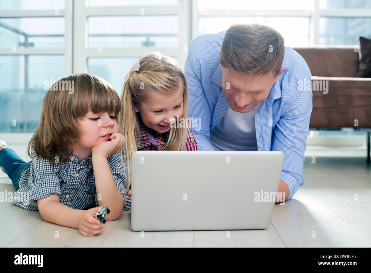 Happy father with children using laptop on floor in living room Stock ...