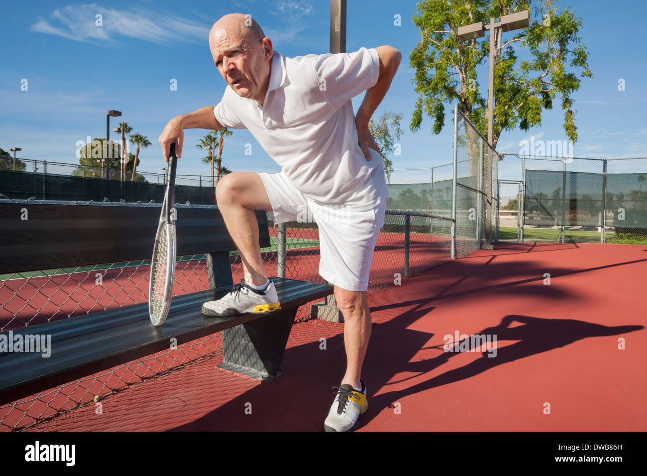 Senior male tennis player with back pain on court Stock Photo - Alamy