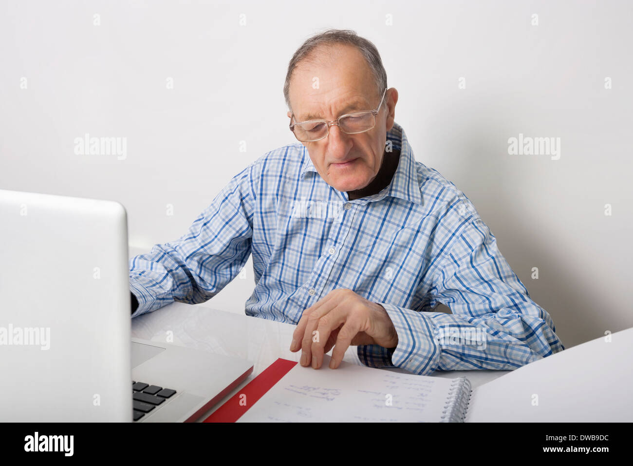 Senior businessman using laptop while reading file at office desk Stock ...