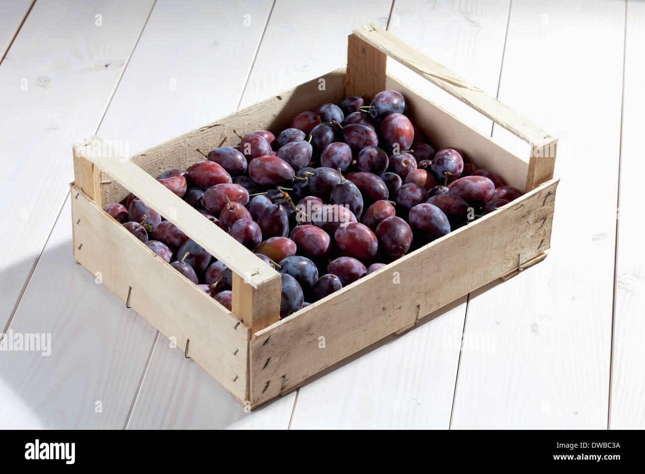 Wooden box with plums on wooden table Stock Photo - Alamy