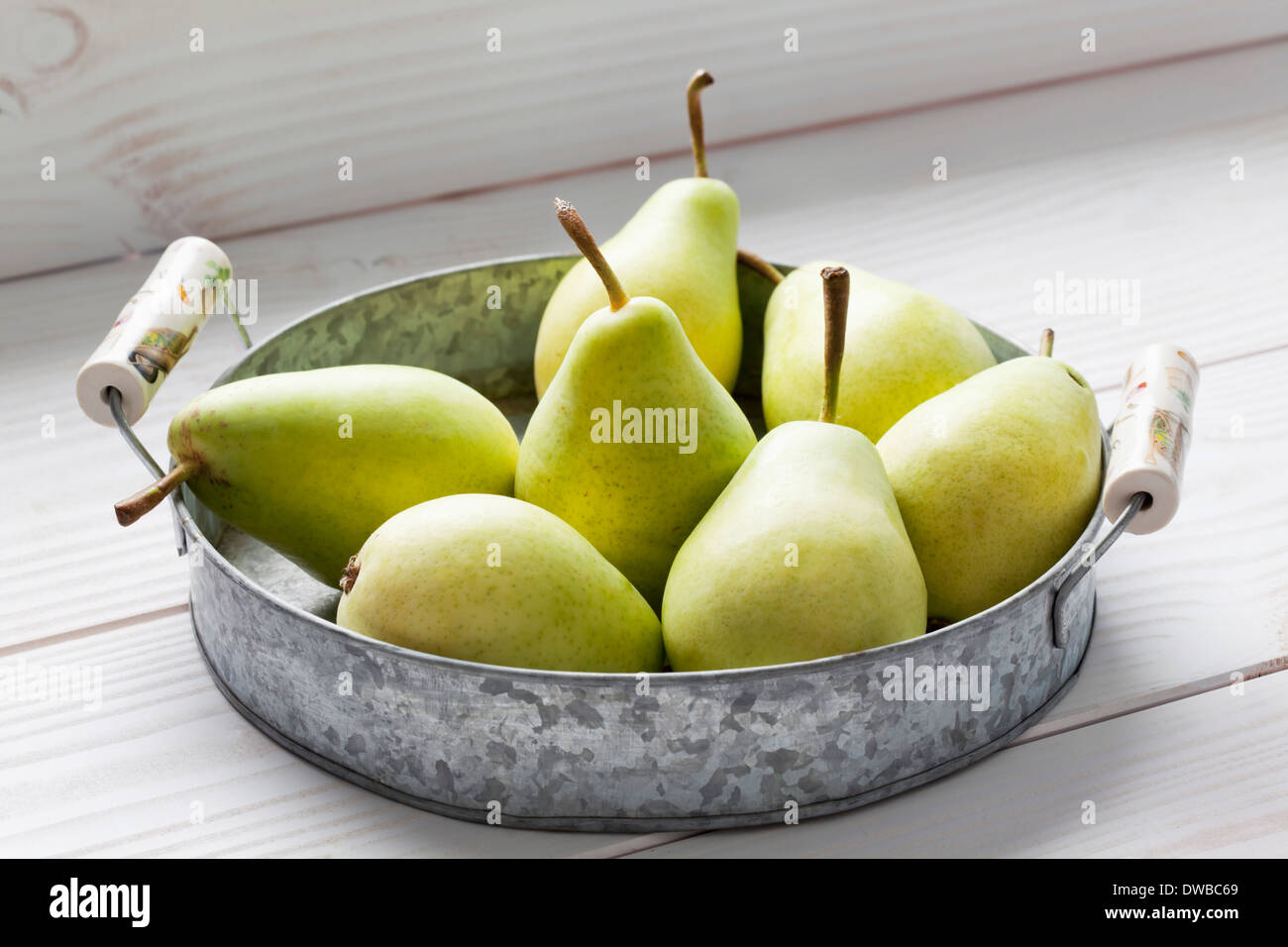 Metal tray of pears (Pyrus) on white wooden table Stock Photo - Alamy