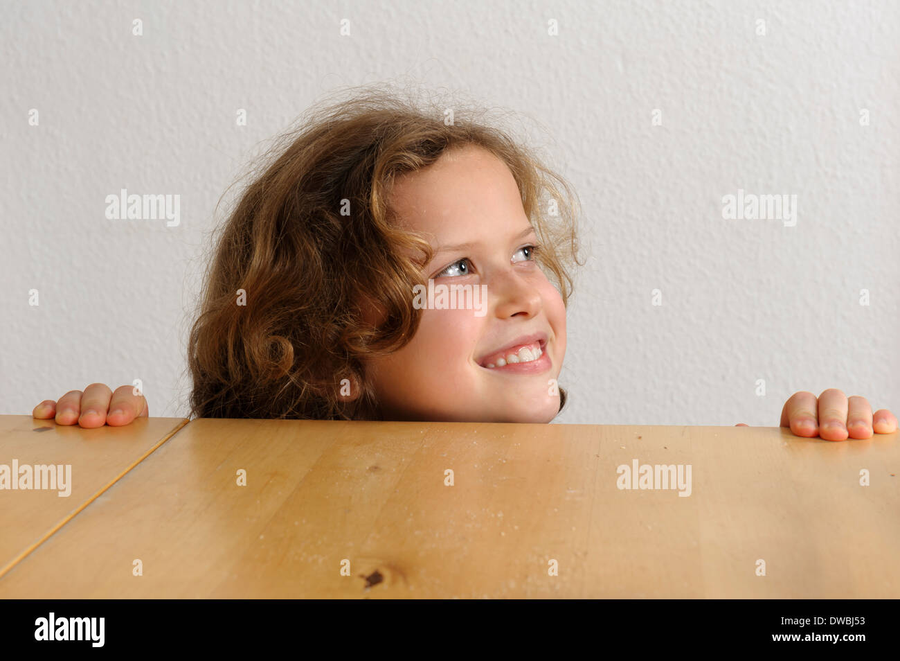 Smiling little girl looking over tabletop Stock Photo - Alamy