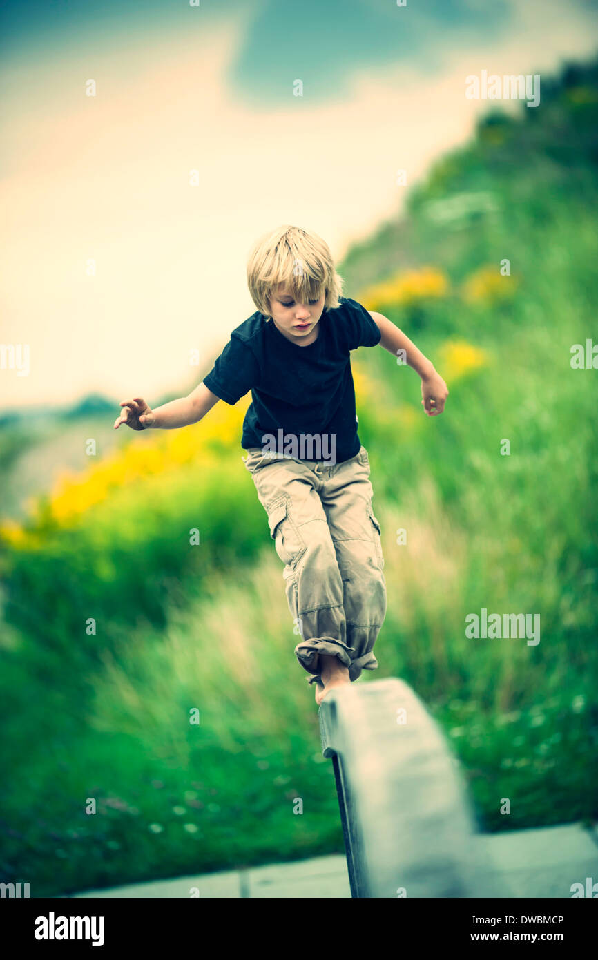 Little boy balancing on railing of wooden boardwalk Stock Photo - Alamy