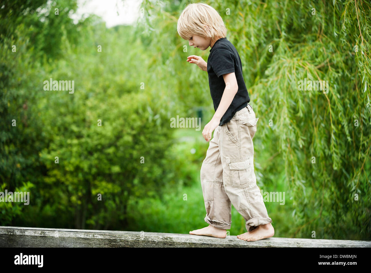 Little boy balancing on railing of wooden boardwalk Stock Photo - Alamy
