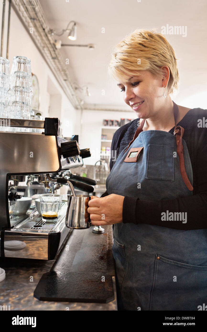 Barista heating up milk using coffee machine Stock Photo - Alamy