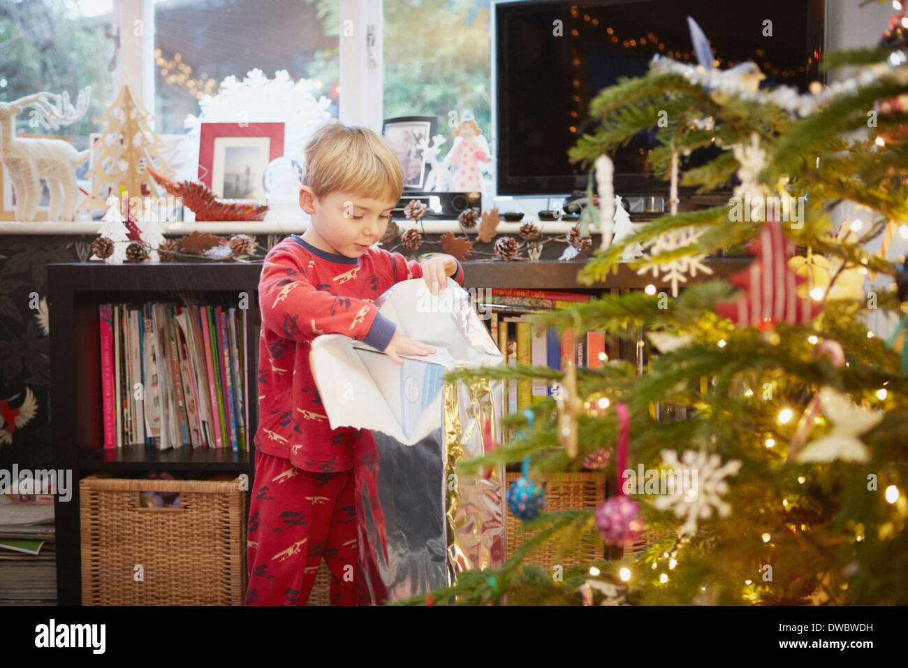 Young boy unwrapping gift at christmas Stock Photo - Alamy