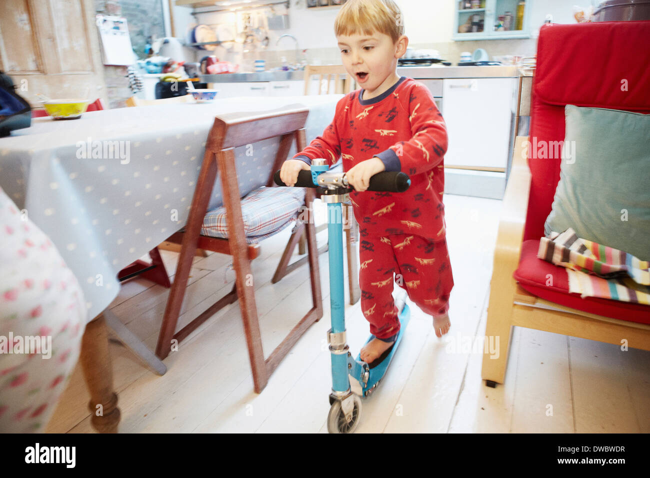Young boy playing on scooter in kitchen Stock Photo - Alamy