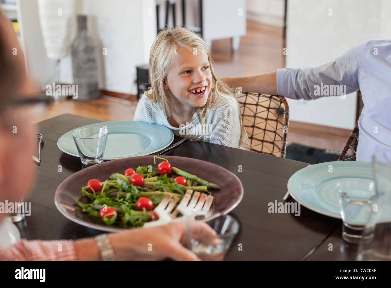 Happy girl having lunch with family at dining table Stock Photo - Alamy