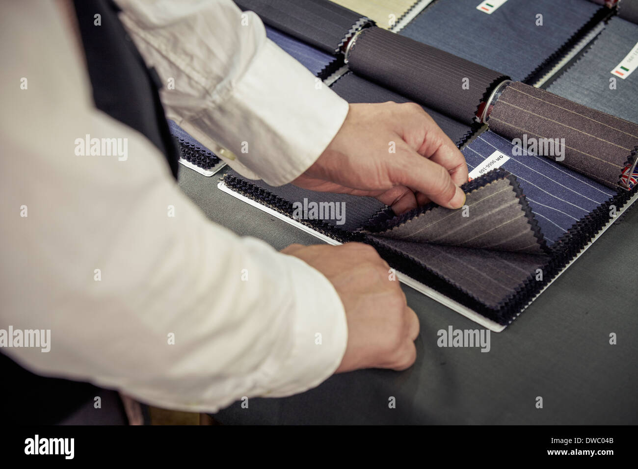 Tailor choosing fabric from swatch in tailors shop Stock Photo - Alamy