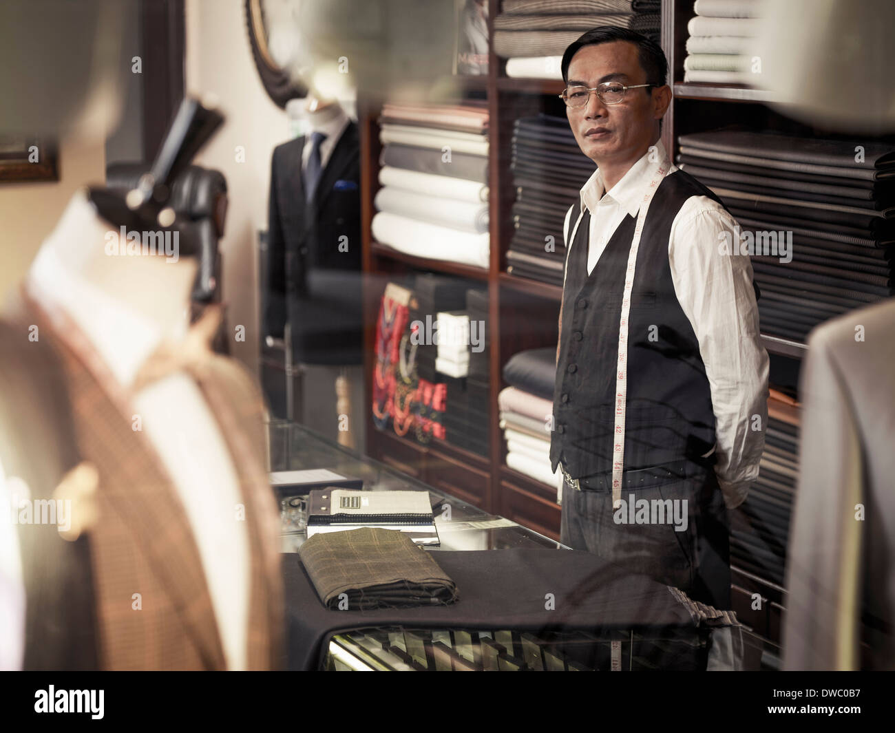 Tailor standing behind counter in tailors shop Stock Photo - Alamy