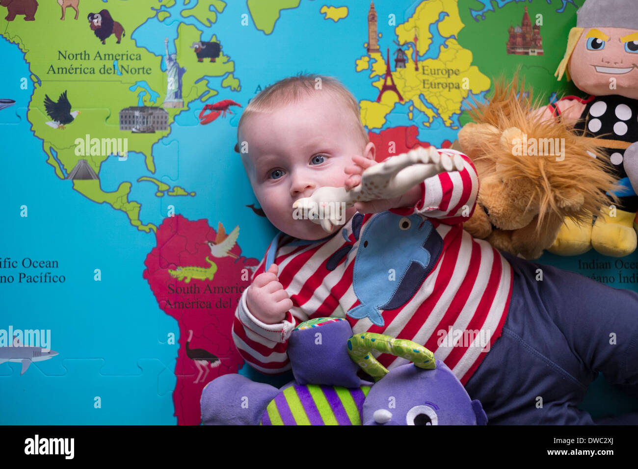 A young baby boy plays with toys on a soft play map of the world Stock ...
