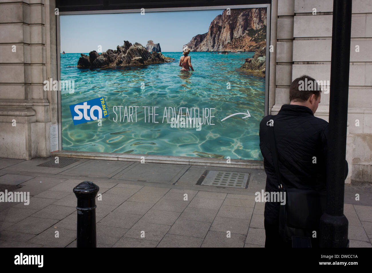 STA Travel adventure poster and waiting pedestrian in a Victoria street ...