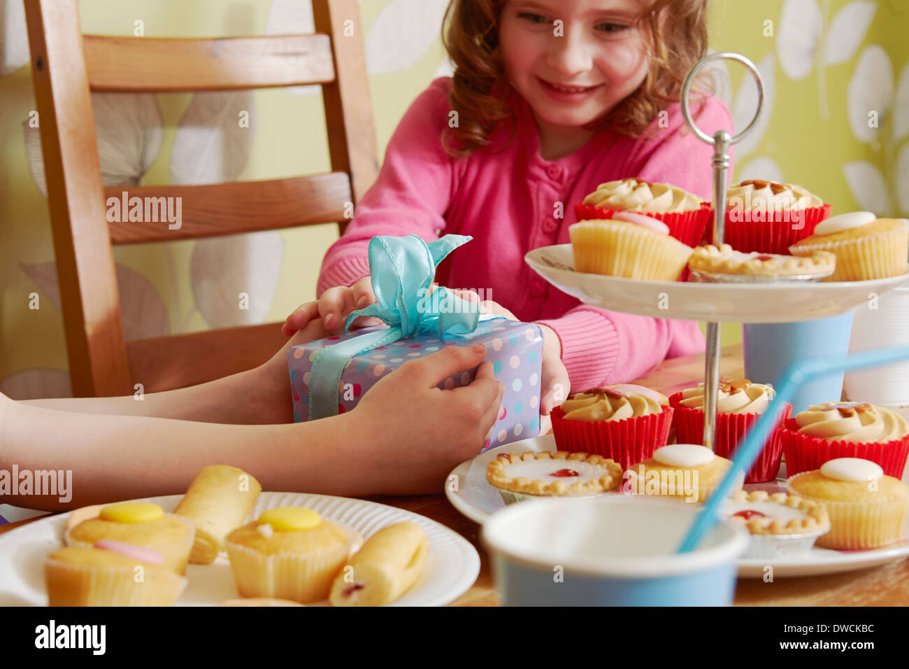 Girl receiving birthday present with cakes on cakestand Stock Photo - Alamy