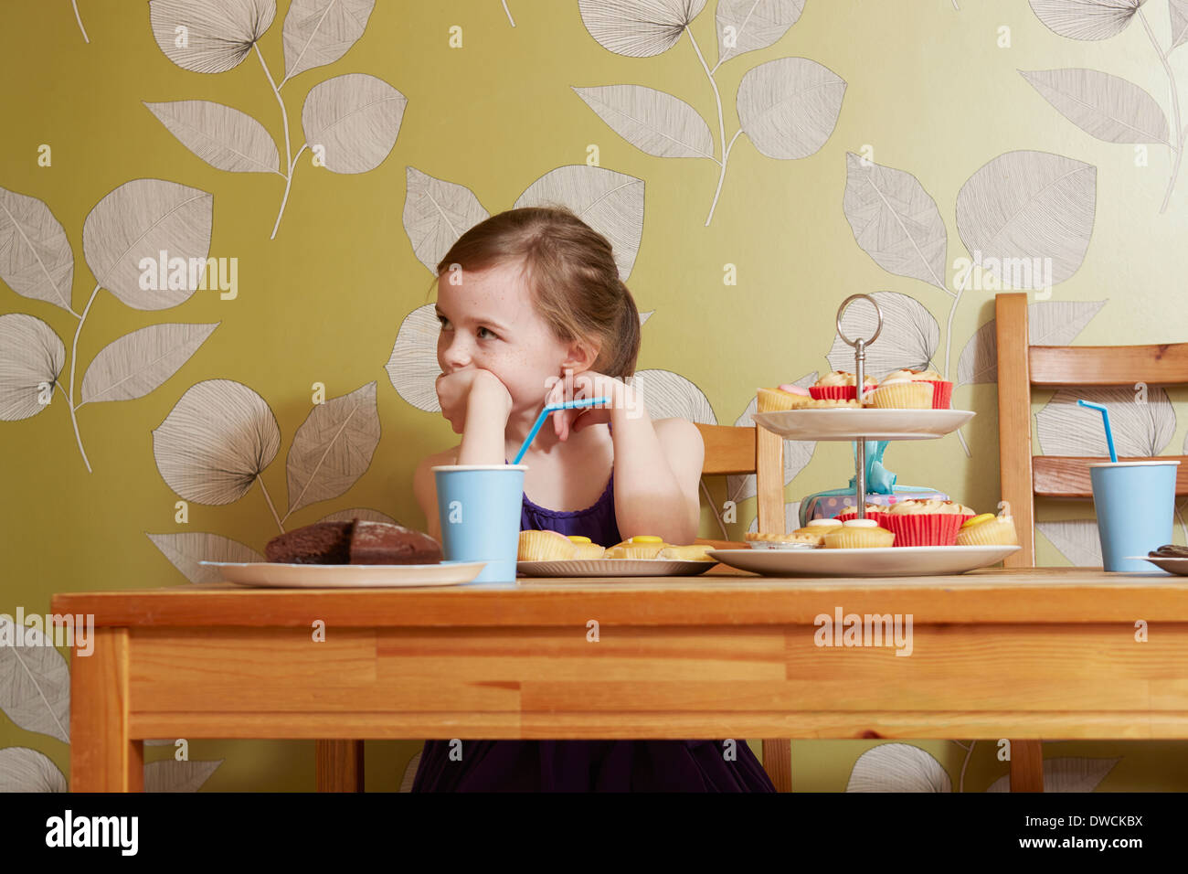 Bored looking girl at table with party food Stock Photo - Alamy