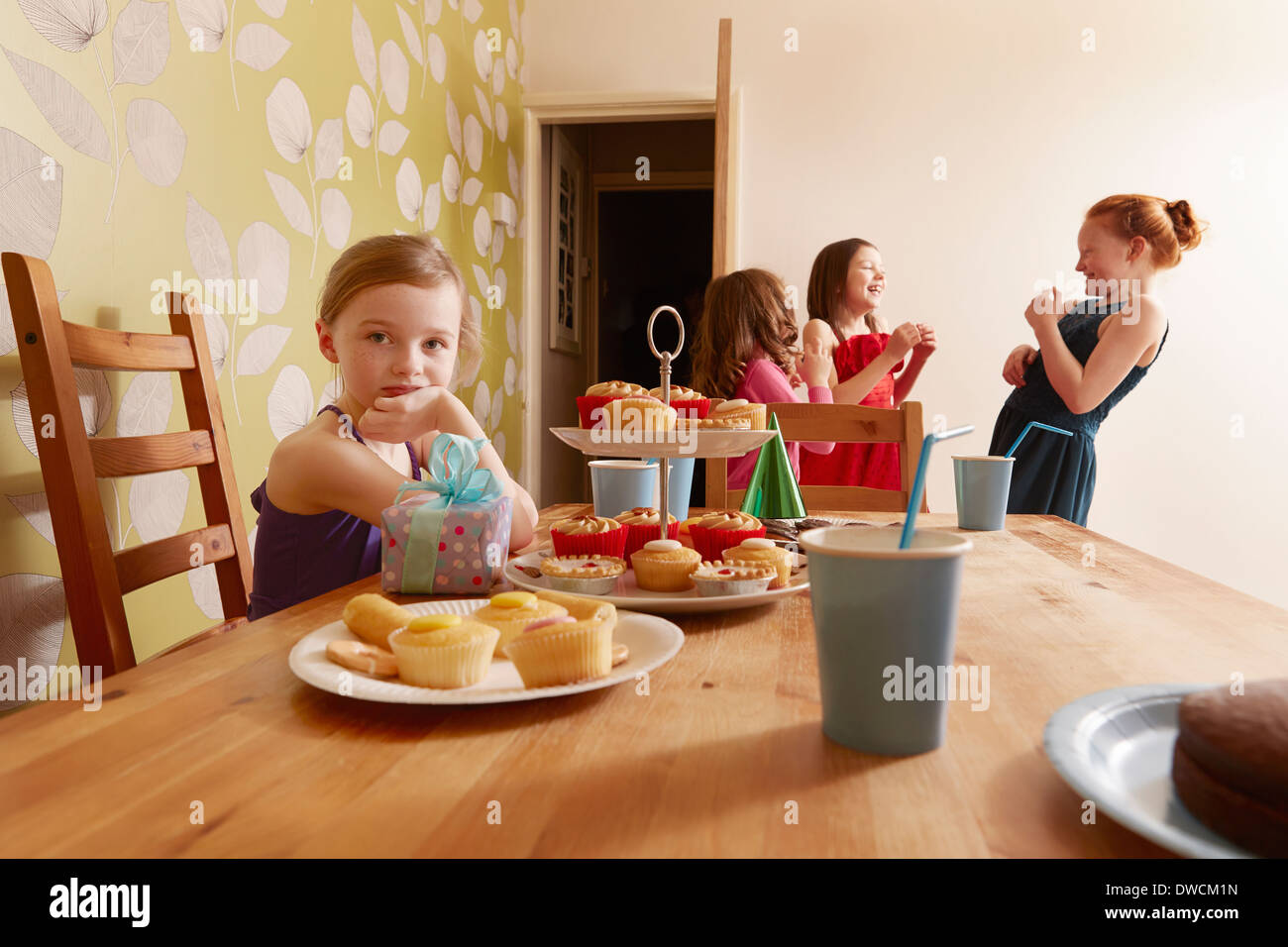 Girl at table with party food, friends in background Stock Photo - Alamy