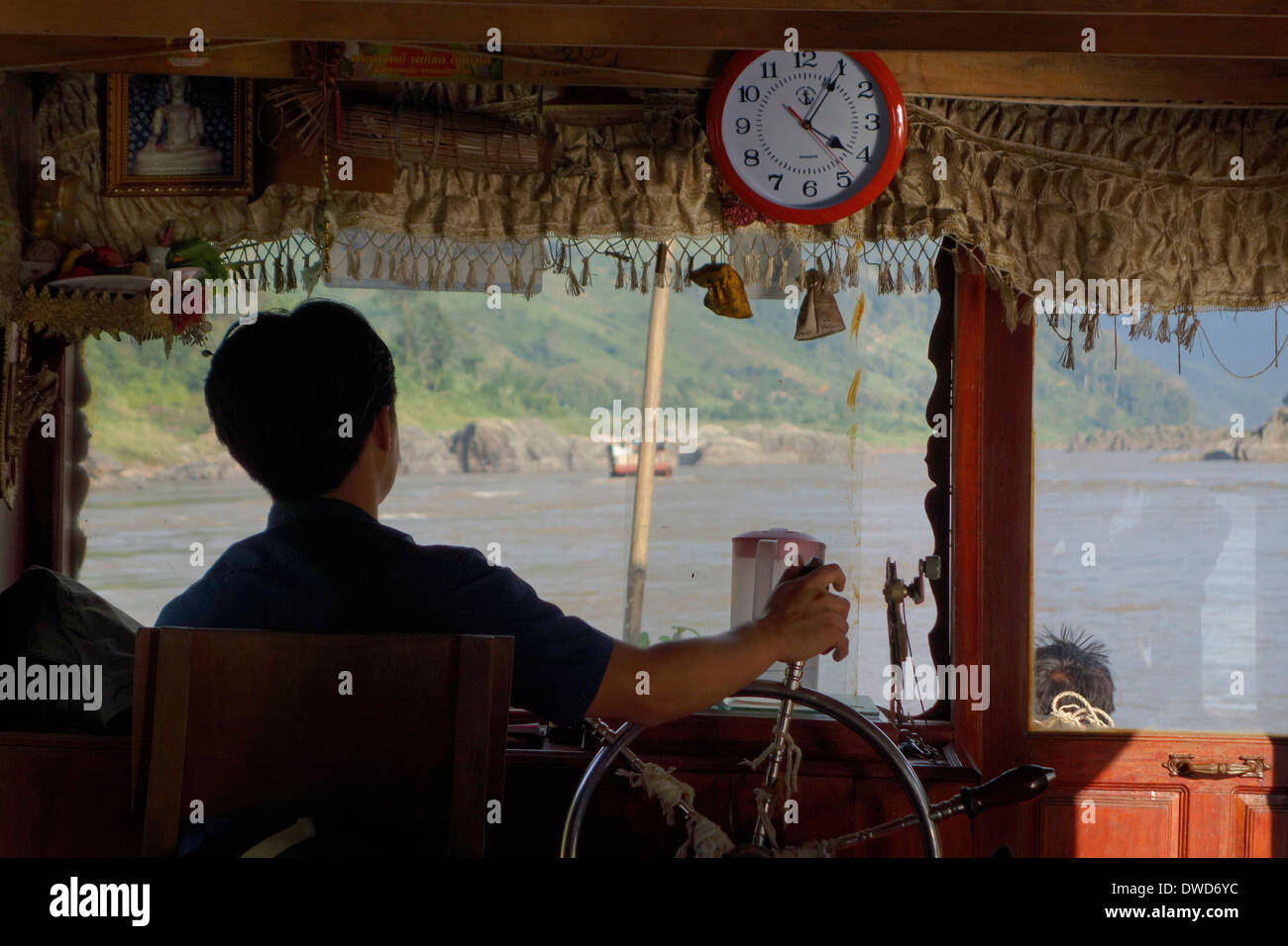 Captain steering a "slow boat" on the Mekong River in Laos Stock Photo ...