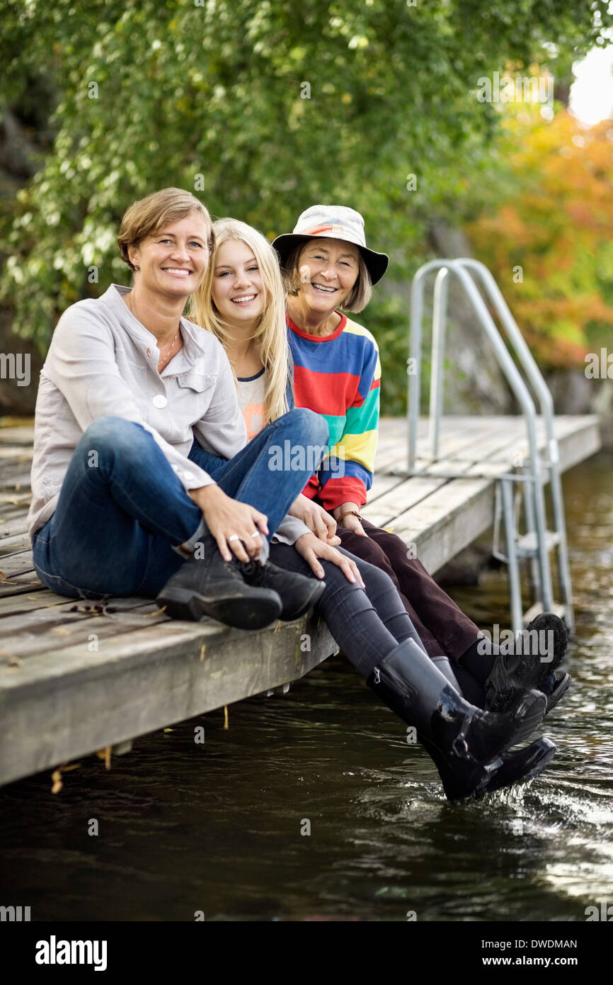 Portrait of three generation females sitting on pier Stock Photo - Alamy