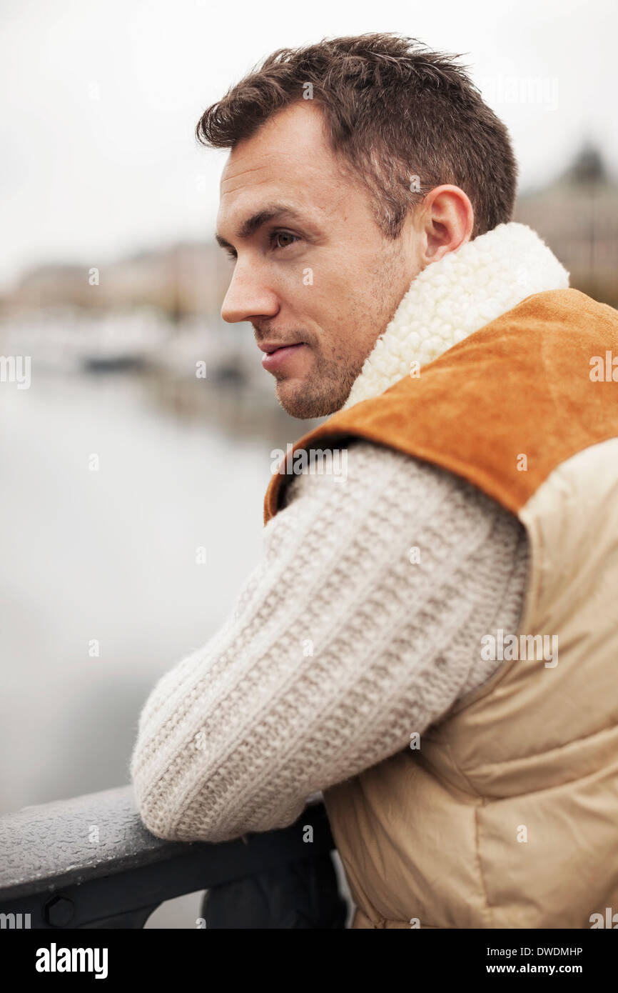Thoughtful young man leaning on railing outdoors Stock Photo - Alamy