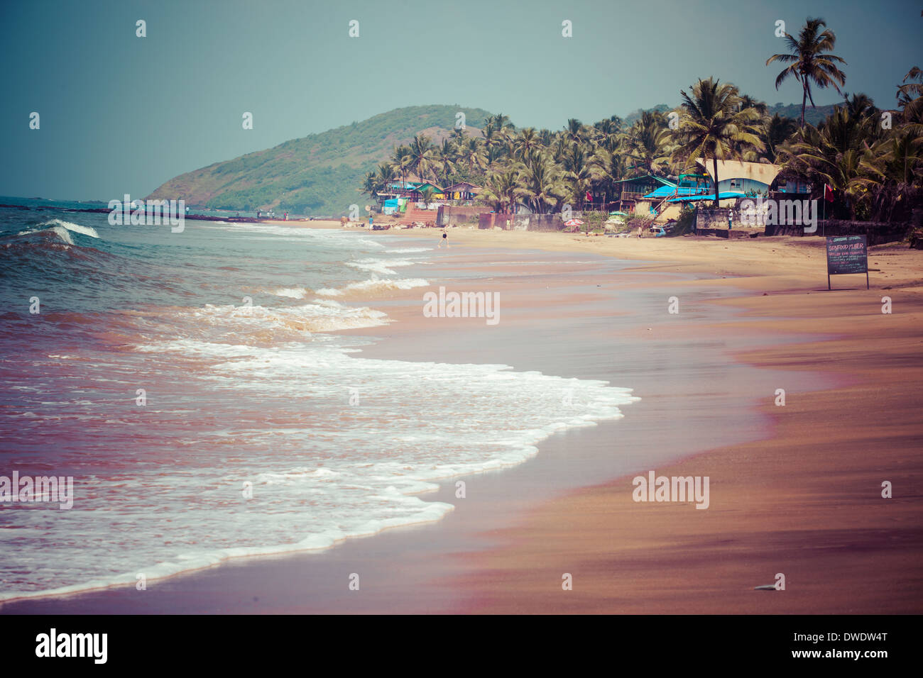 Exiting Anjuna beach panorama on low tide with white wet sand and green ...