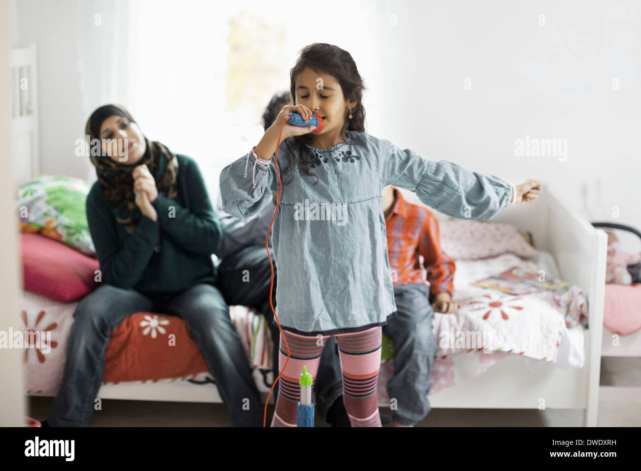 Muslim family listening to girl singing in bedroom Stock Photo - Alamy