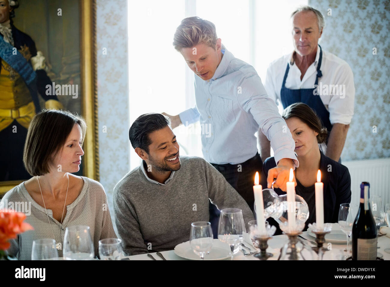 Waiter serving water to business people at restaurant with chef ...