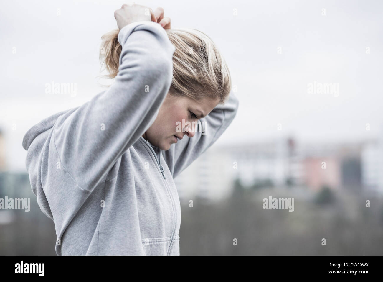 Side view of sporty woman tying hair outdoors Stock Photo - Alamy