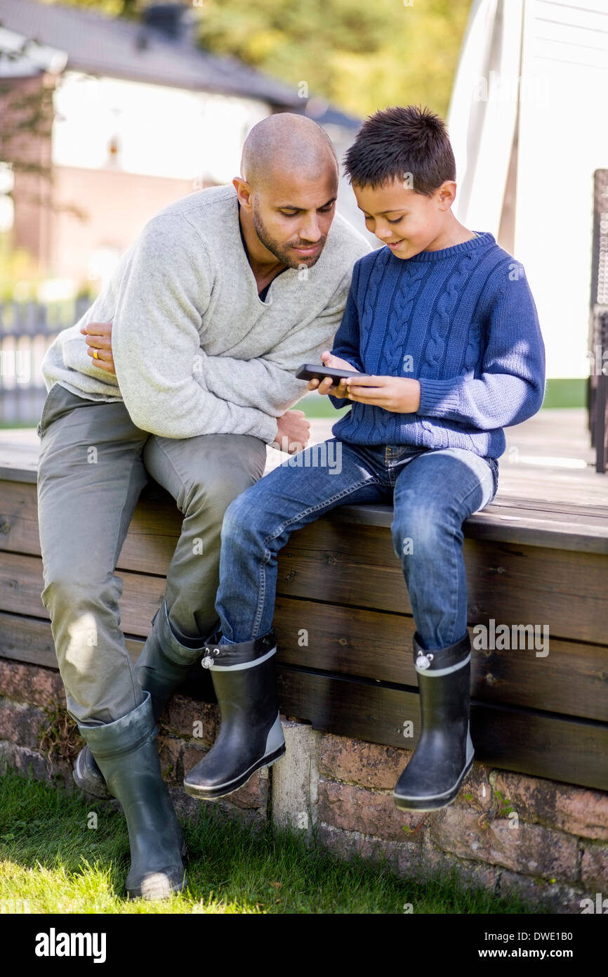 Father and son using mobile phone at yard Stock Photo - Alamy