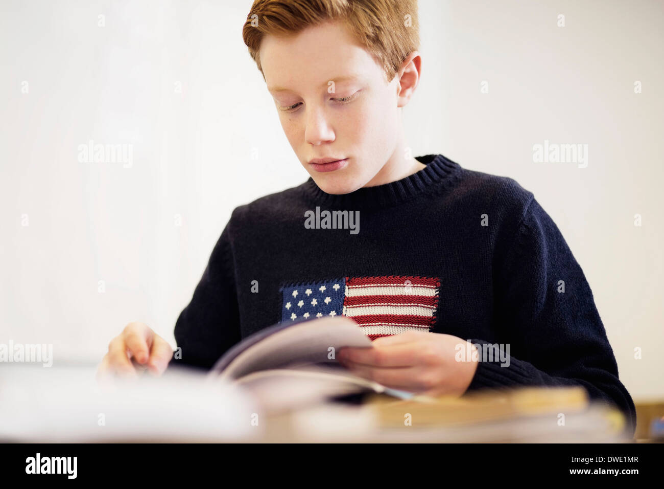 High school boy reading book in classroom Stock Photo - Alamy
