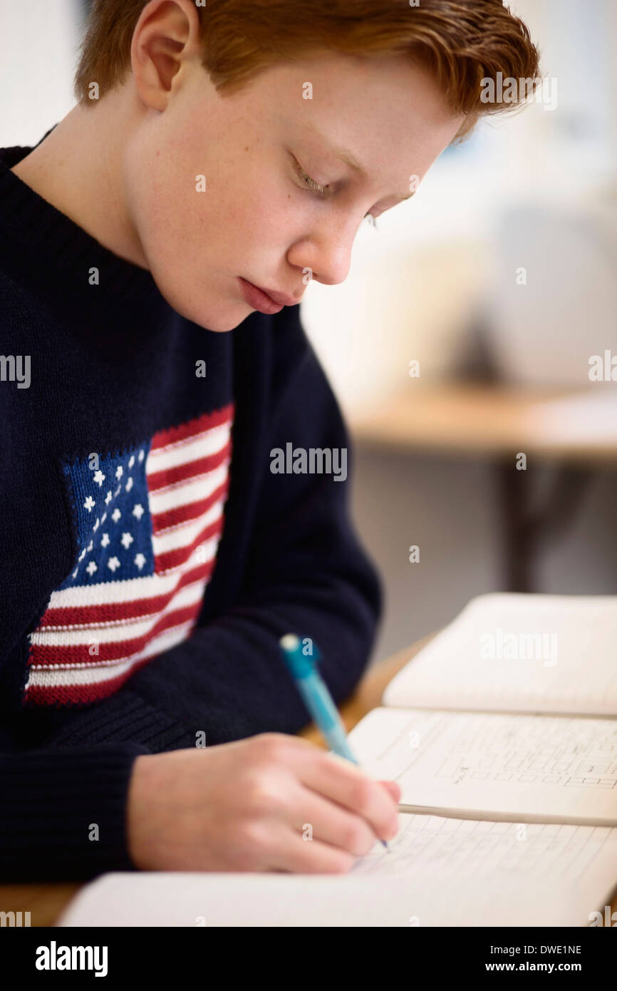 High school boy writing at desk in classroom Stock Photo - Alamy