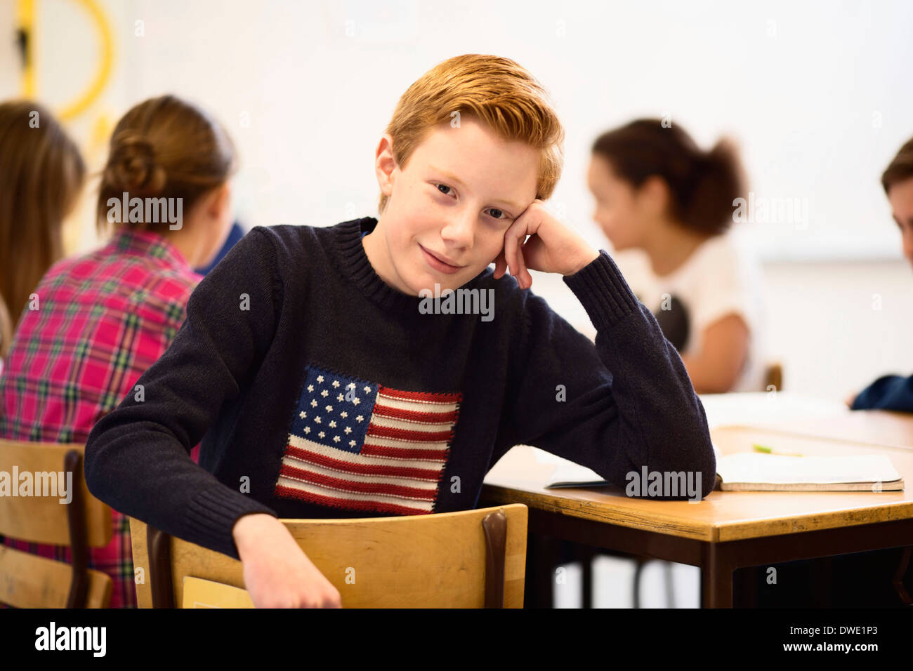 Portrait of confident schoolboy sitting at desk in classroom Stock ...