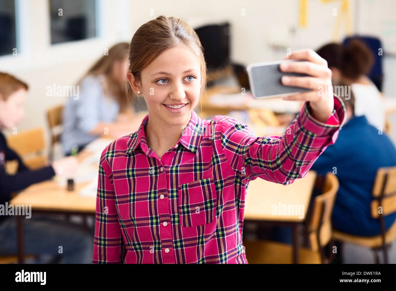 Smiling schoolgirl taking self-portrait in classroom Stock Photo - Alamy