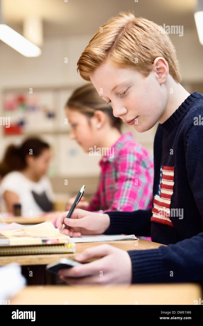 High school student using mobile phone while studying in classroom ...