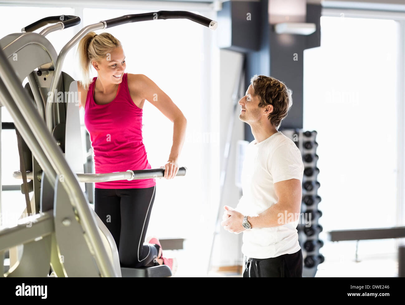 Instructor talking to customer exercising at gym Stock Photo - Alamy