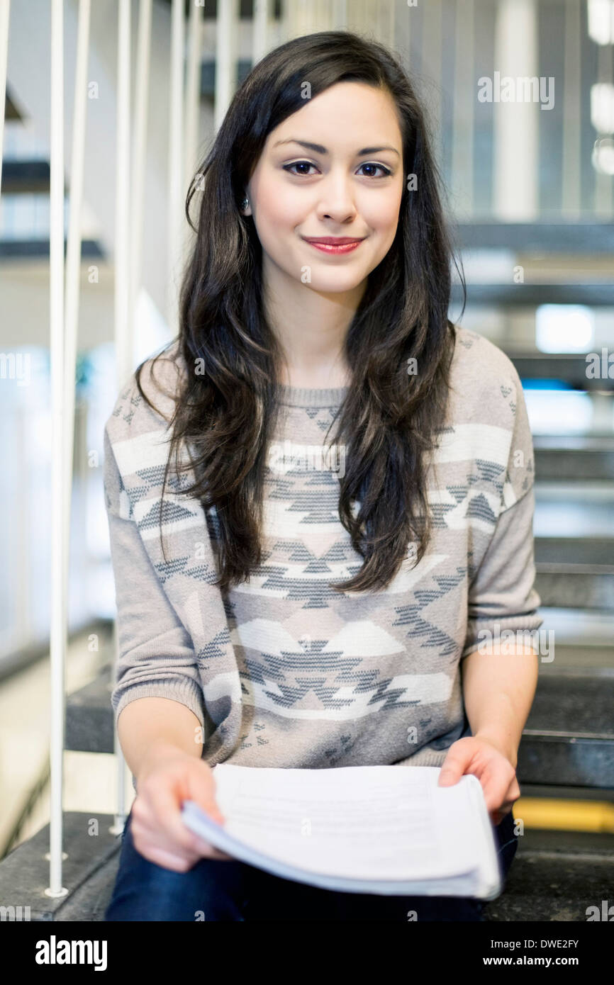 Portrait of confident female student sitting on steps at university ...