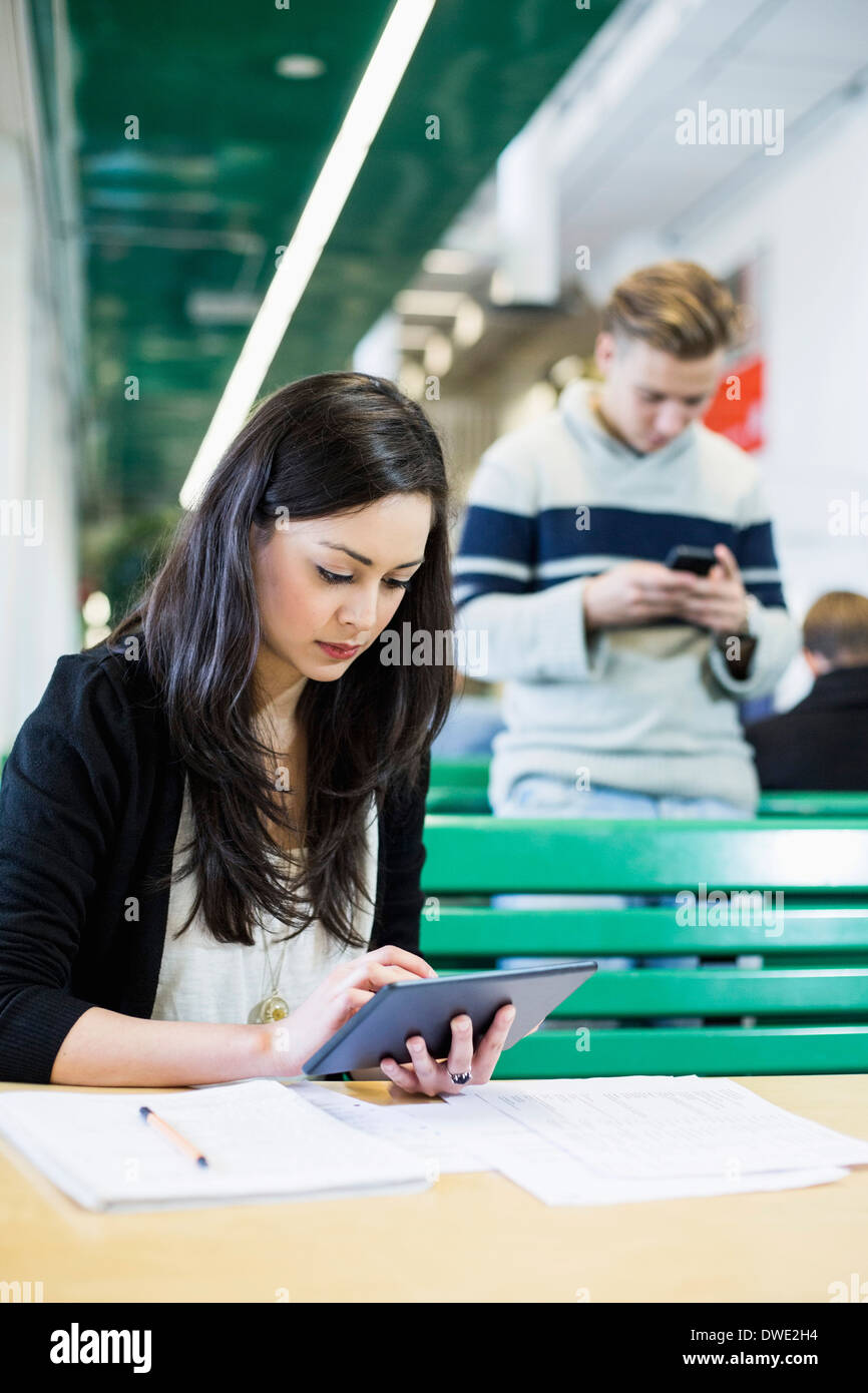 Female university student using digital tablet with friend in ...