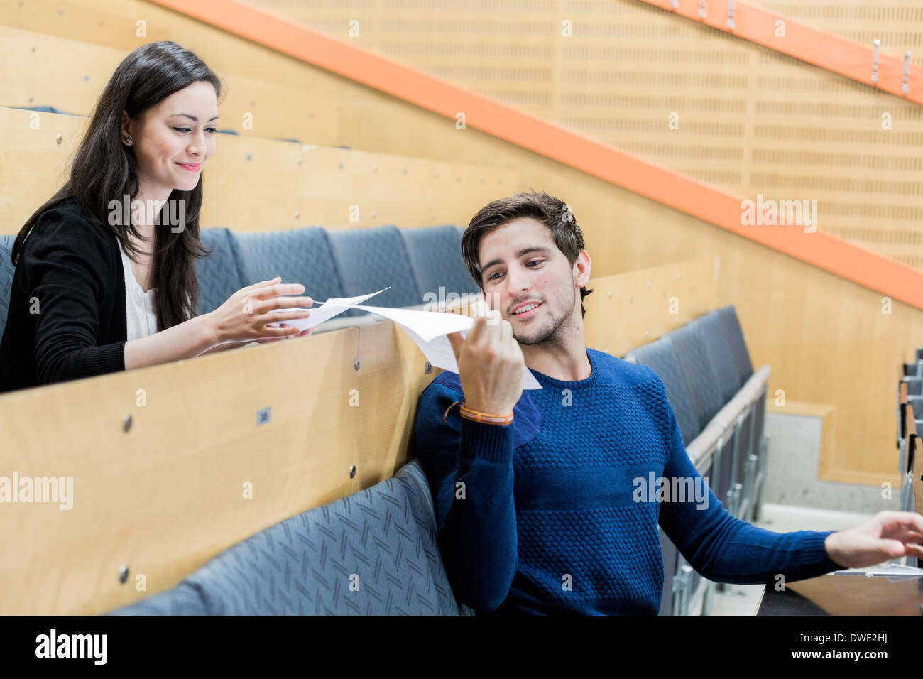 Male student passing paper to female friend in classroom Stock Photo ...
