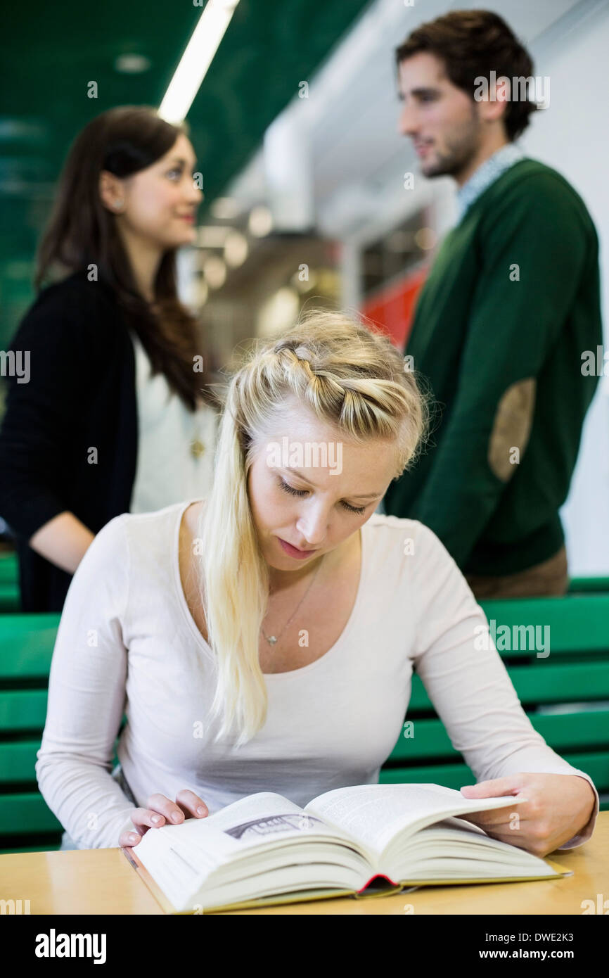 University student studying in common room with friends standing in ...