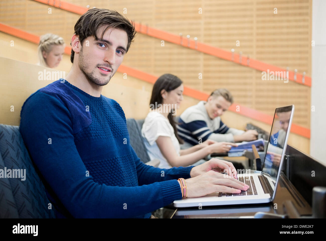 Portrait of confident university student using laptop in classroom ...