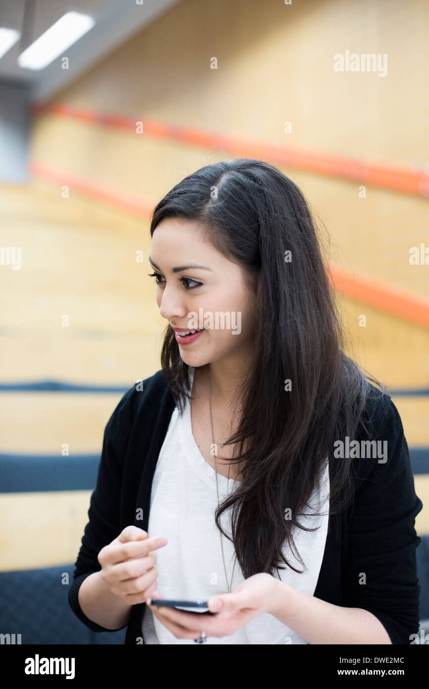 Female university student holding mobile phone in classroom Stock Photo ...