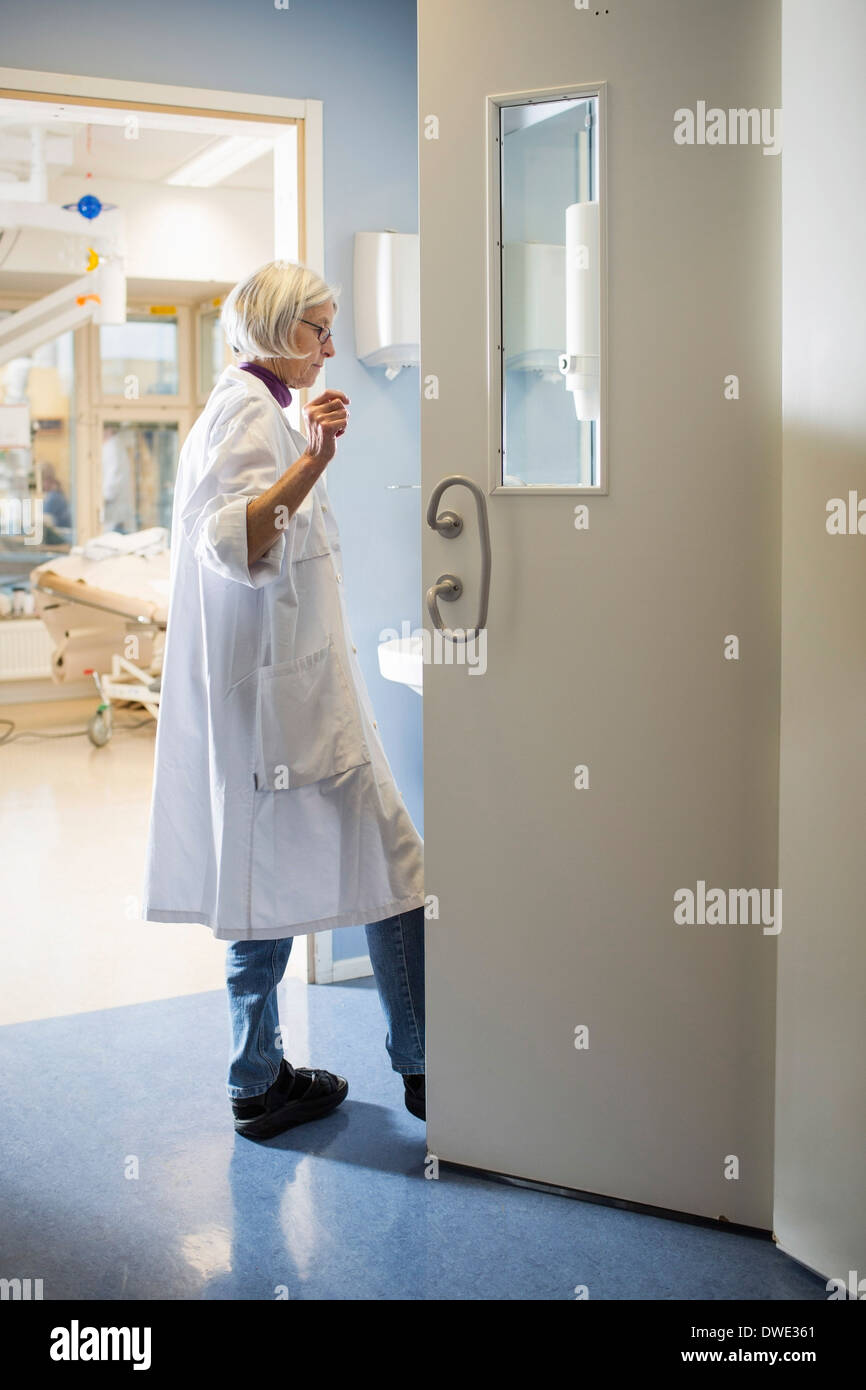 Full length side view of senior female doctor entering hospital ...