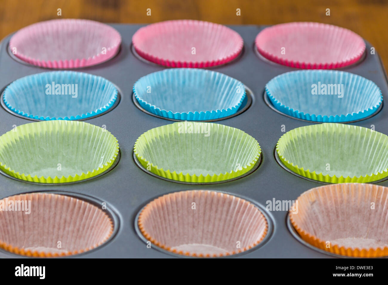 baking sheet for muffins equipped with paper cups in different colors ...