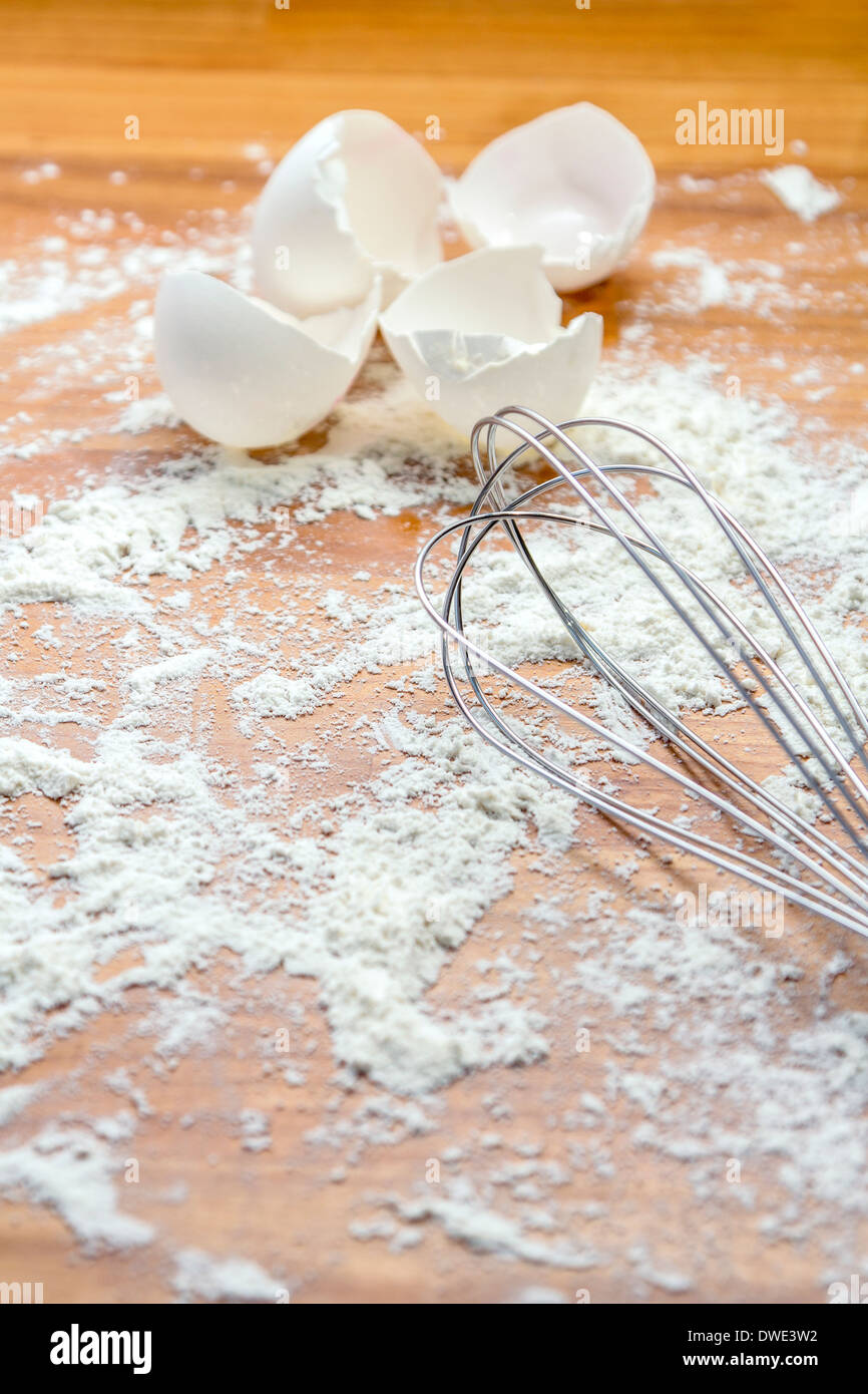 Silver Egg Whip with eggshells and some flour on a wooden table Stock ...