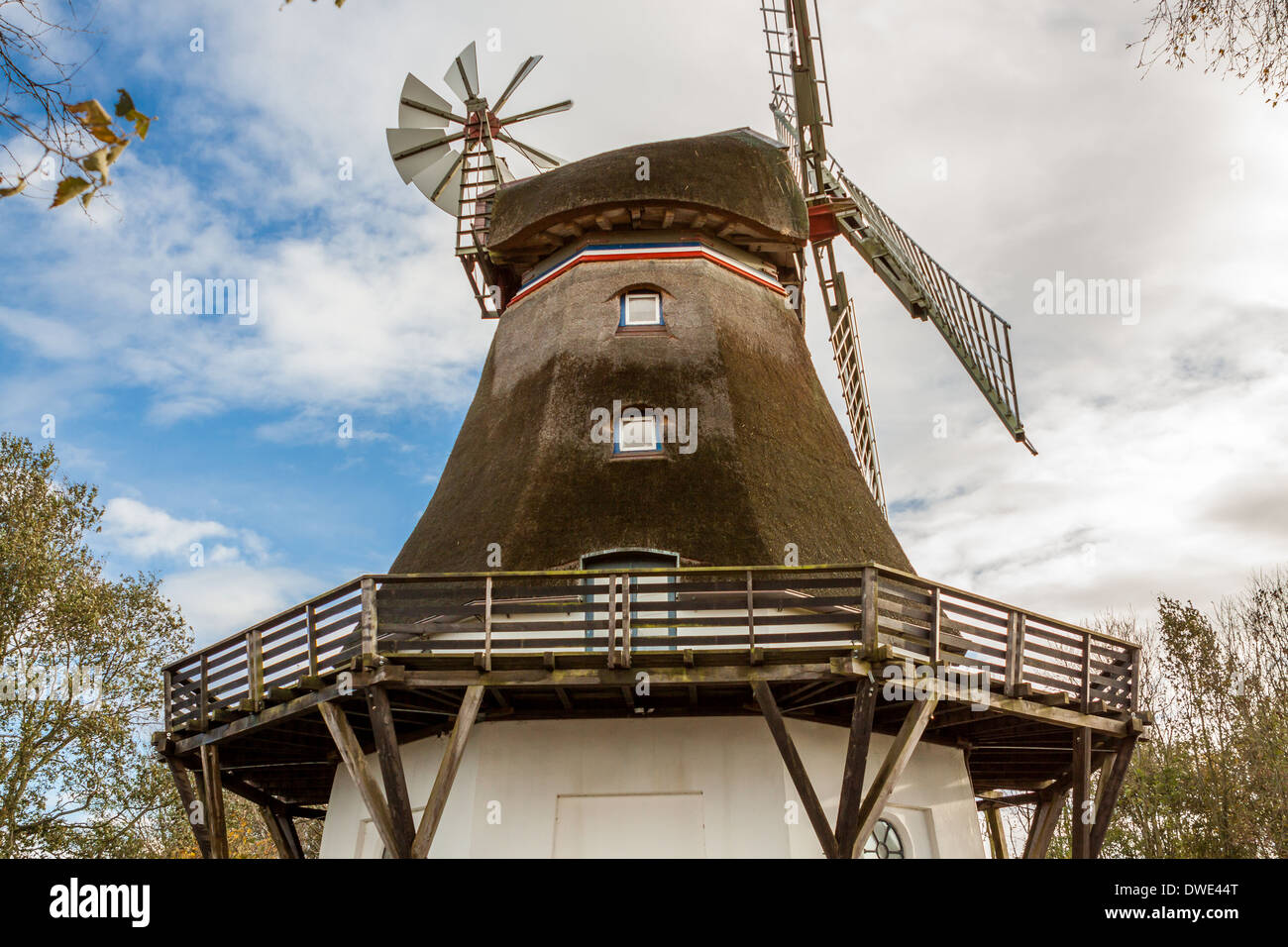Traditional wooden windmill in a lush garden with four sails or blades ...